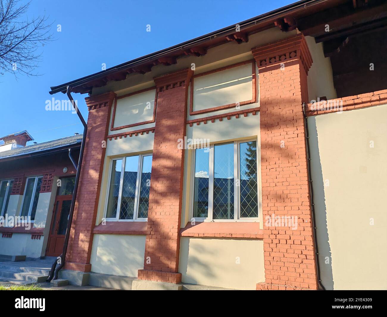 A traditional building with red accents and a tall, sloped roof, framed ...