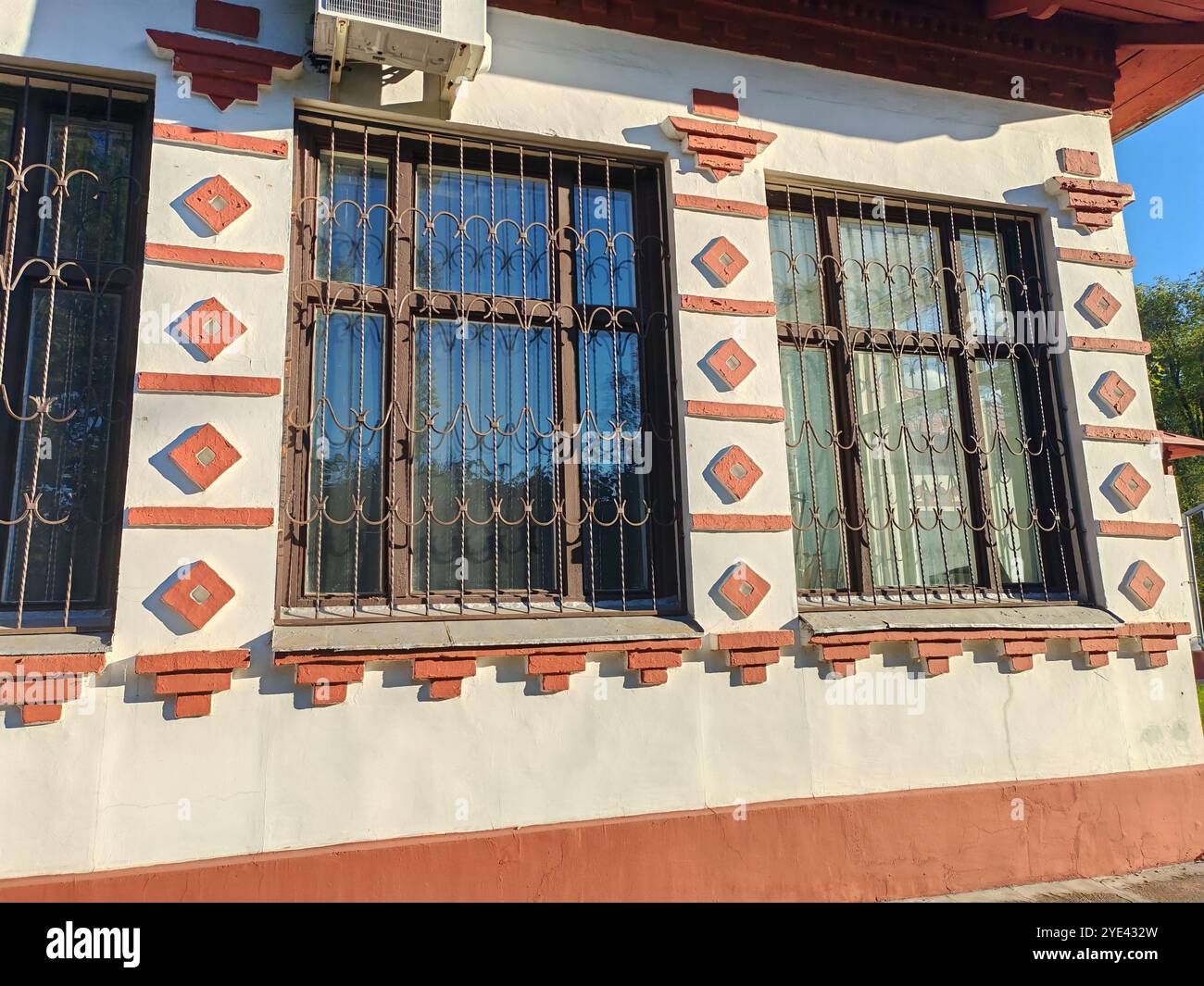 A series of windows with ornate metal bars and red brick accents ...