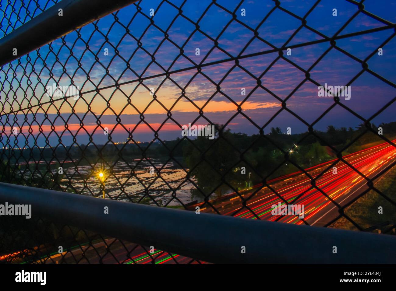 Street Scene with vehicle lights seen through the silhouette of a chain ...
