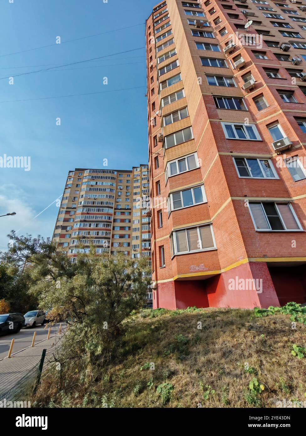 A tall red and beige brick residential building with multiple balconies ...