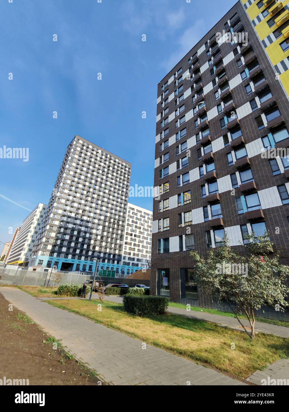 Two modern high-rise apartment buildings, one with a yellow and white ...