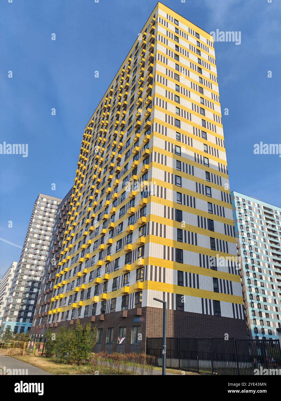 Two high-rise residential buildings, one yellow and white, the other ...