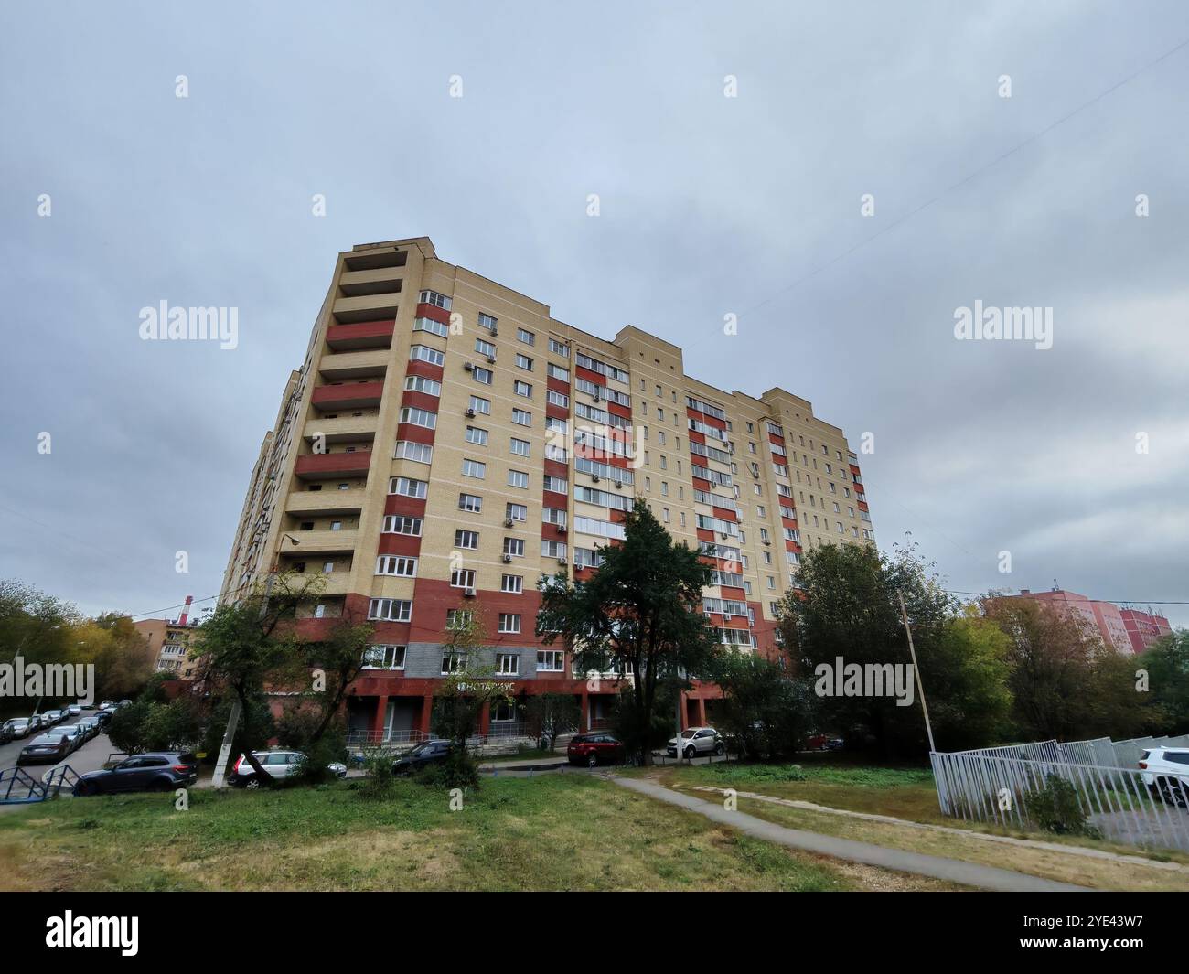 tall residential building with pastel-colored balconies and windows ...