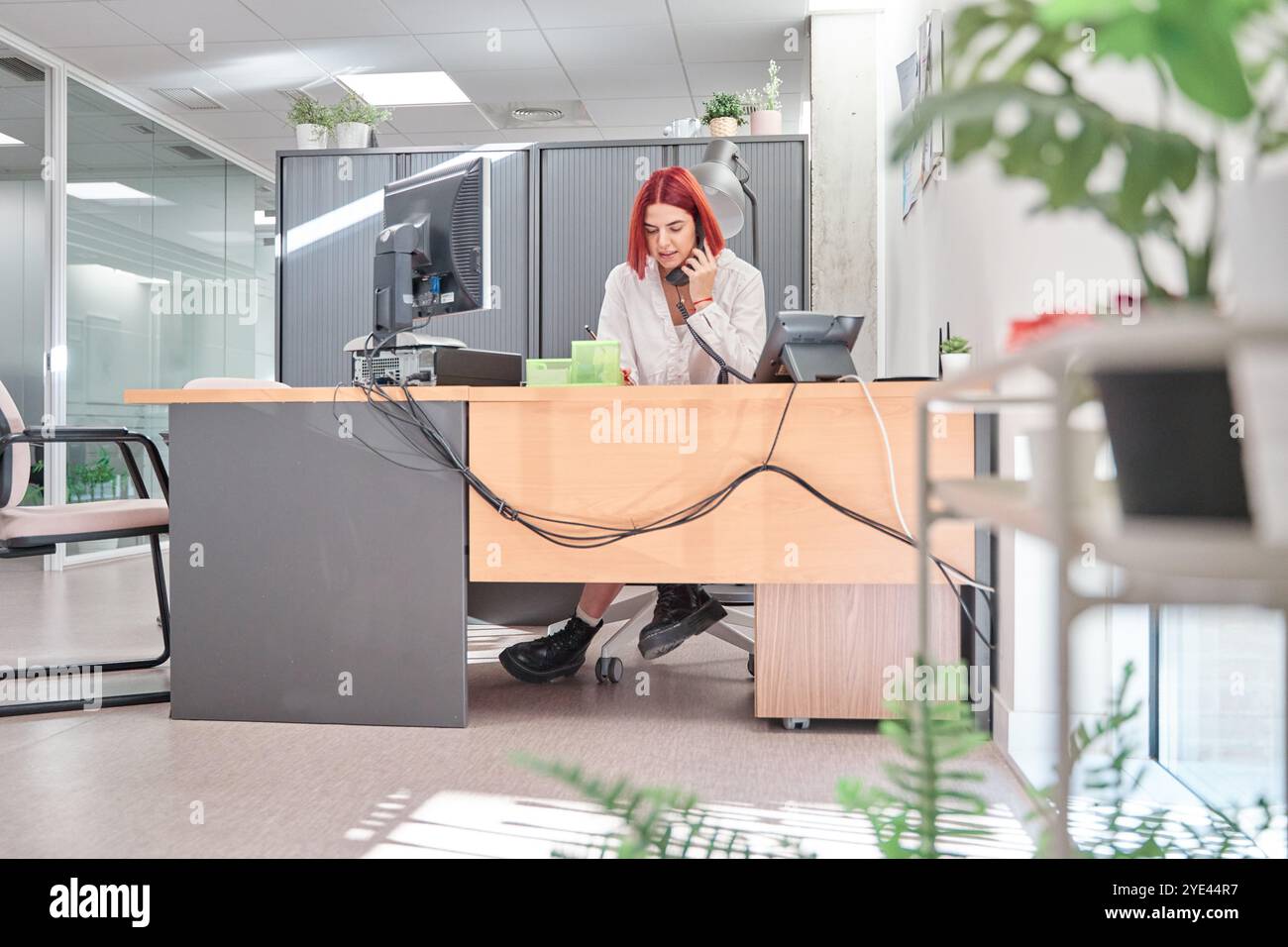 a full view of a young woman sitting at an office desk or clinic ...