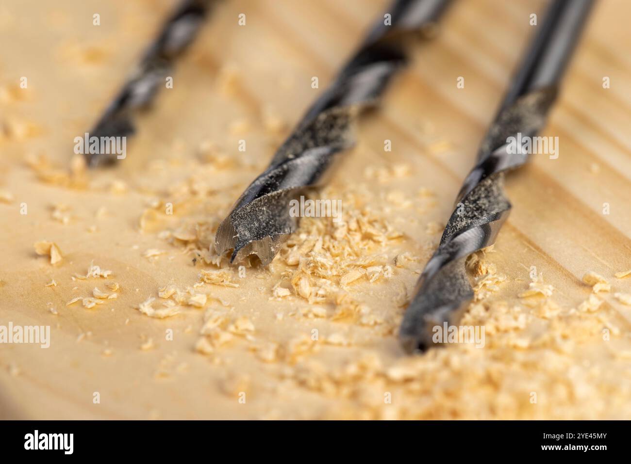 metal drill bit and pine wood board during operation, close-up of pine ...