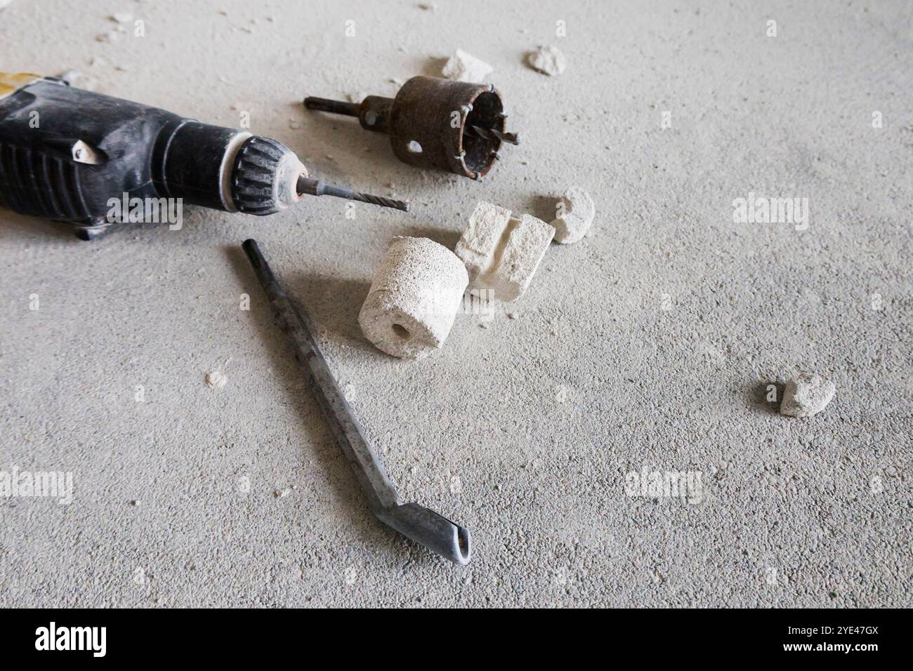 A drill and a wrench are currently laying on the floor, appearing to be ...