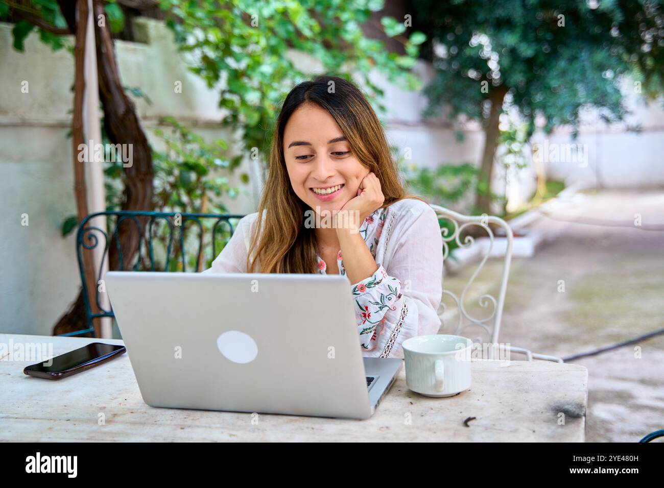 young woman working or studying in her backyard on her laptop computer ...