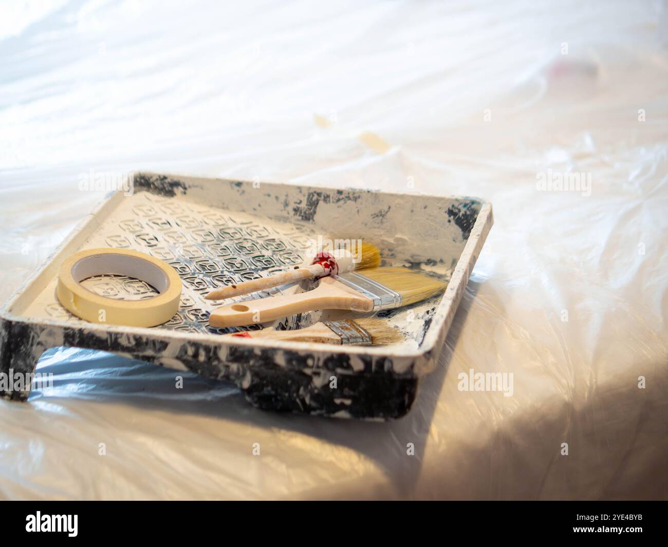 some paintbrushes and a roll of masking tape on a paint tray Stock ...