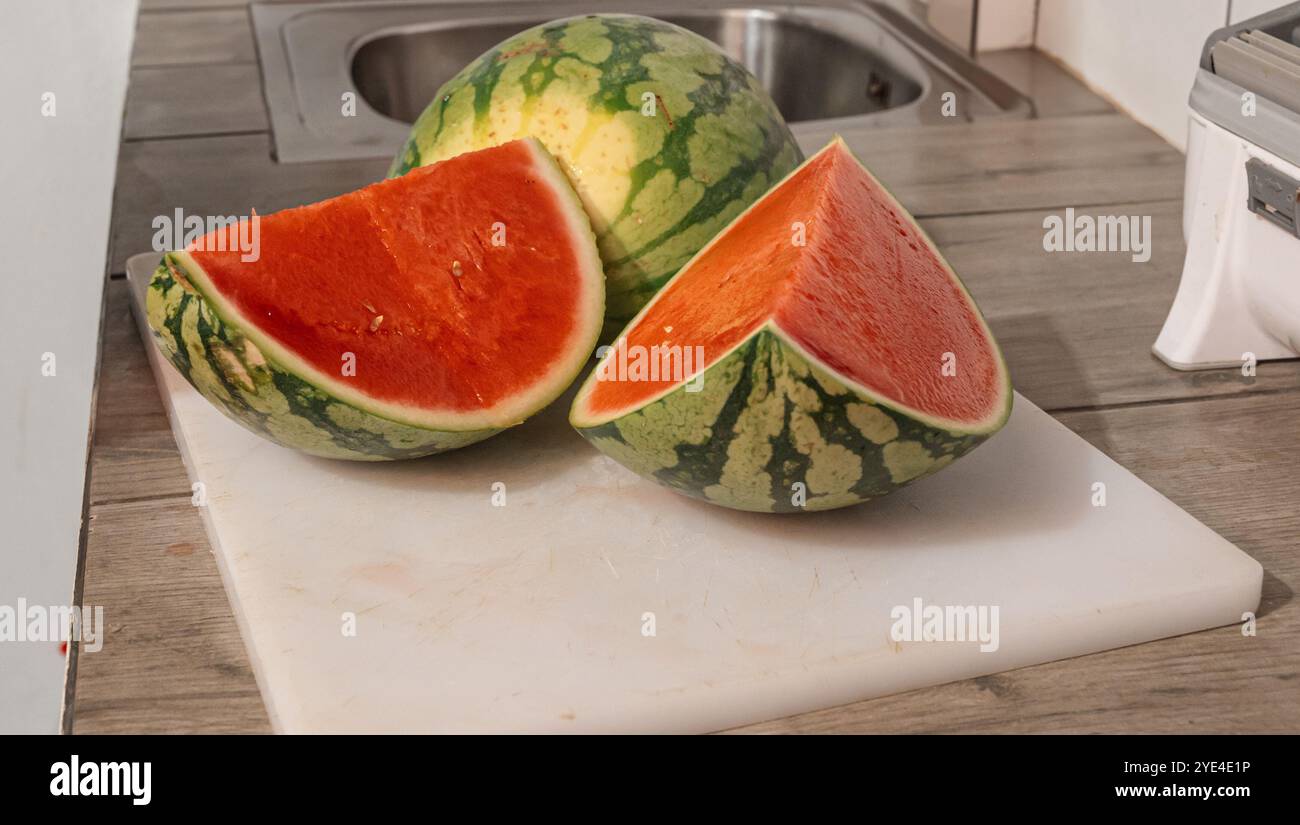 A watermelon cut on a chopping board. The watermelon is cut into three ...