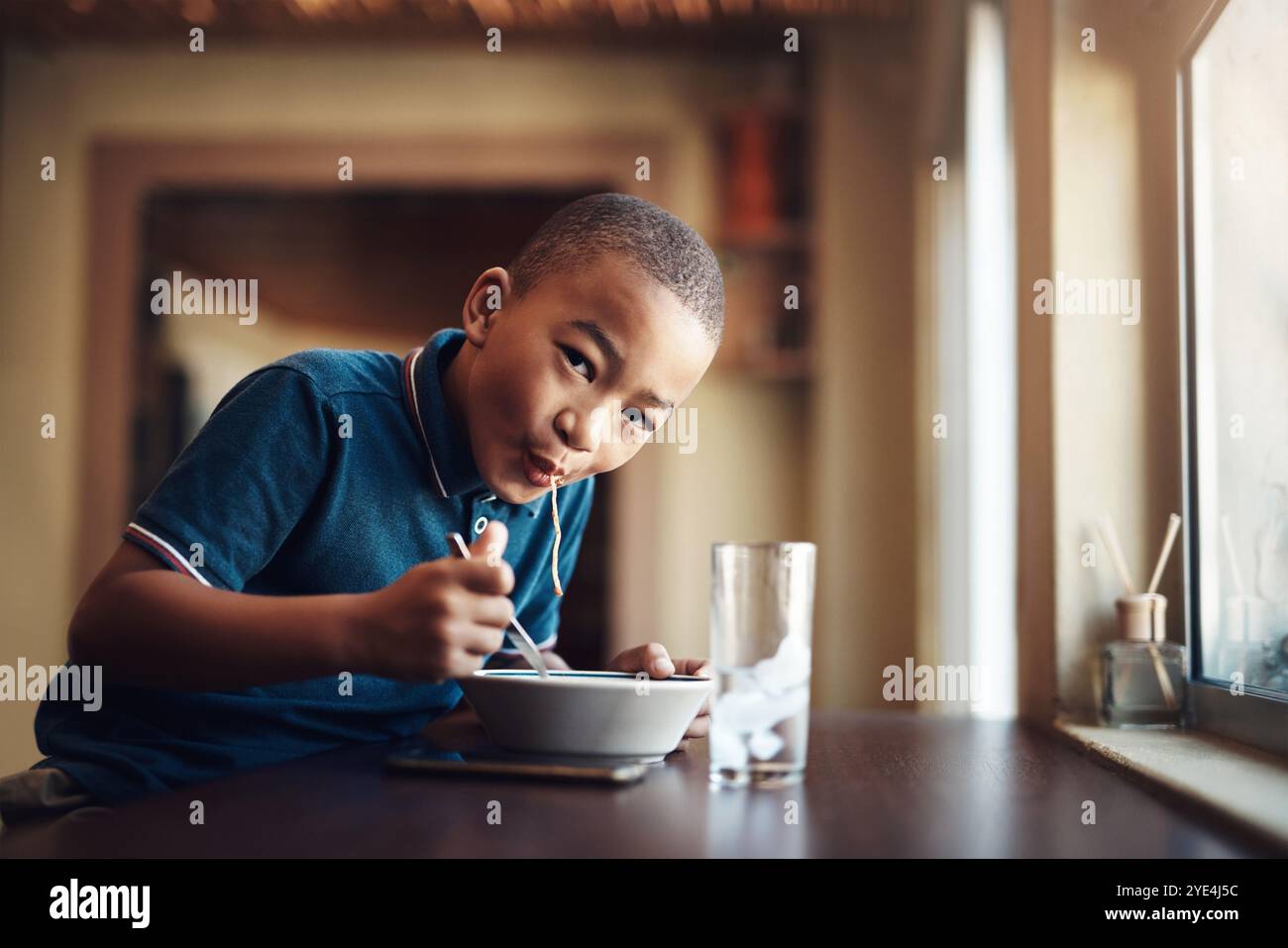 Child, portrait and eating pasta in home for nutrition, hungry or ...