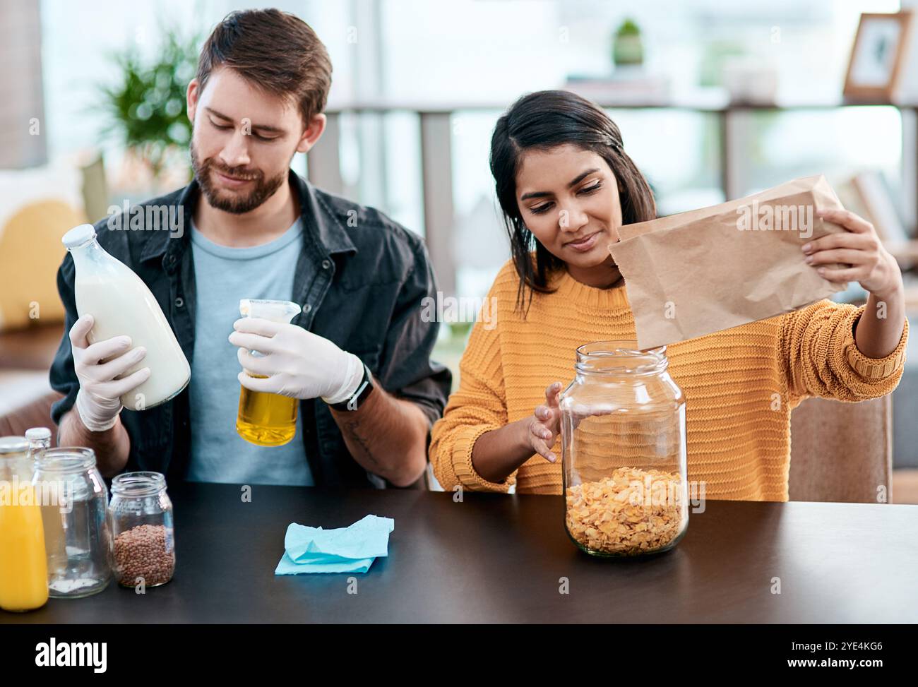 Cereal, jar and sanitizing with interracial couple in kitchen of home ...