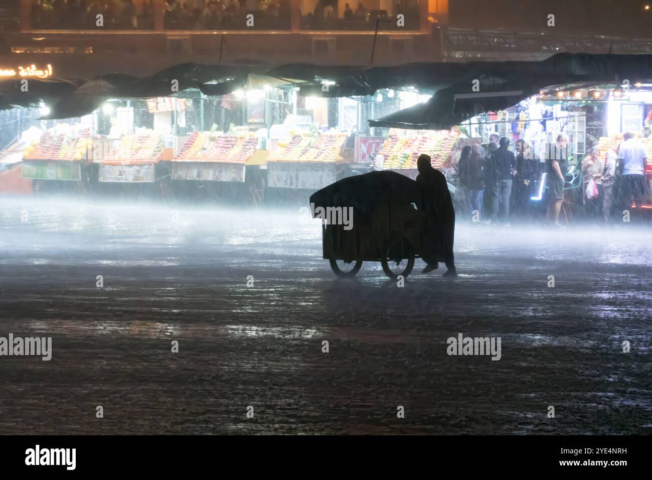 Marrakesh, Morocco. A market trader pushes a cart across Jemaa el-Fnaa ...