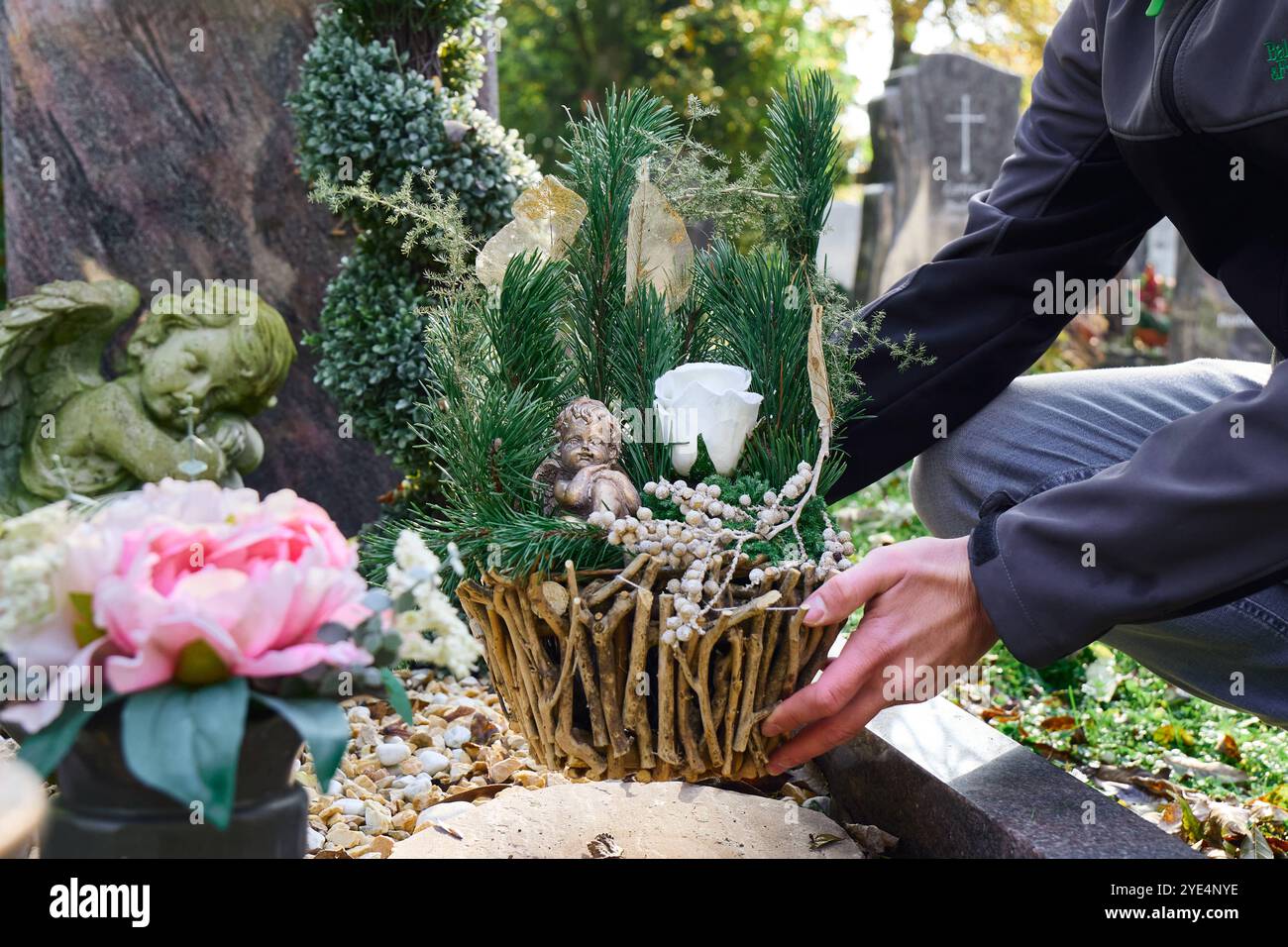 Bavaria, Germany - October 29, 2024: Man places a grave arrangement on ...