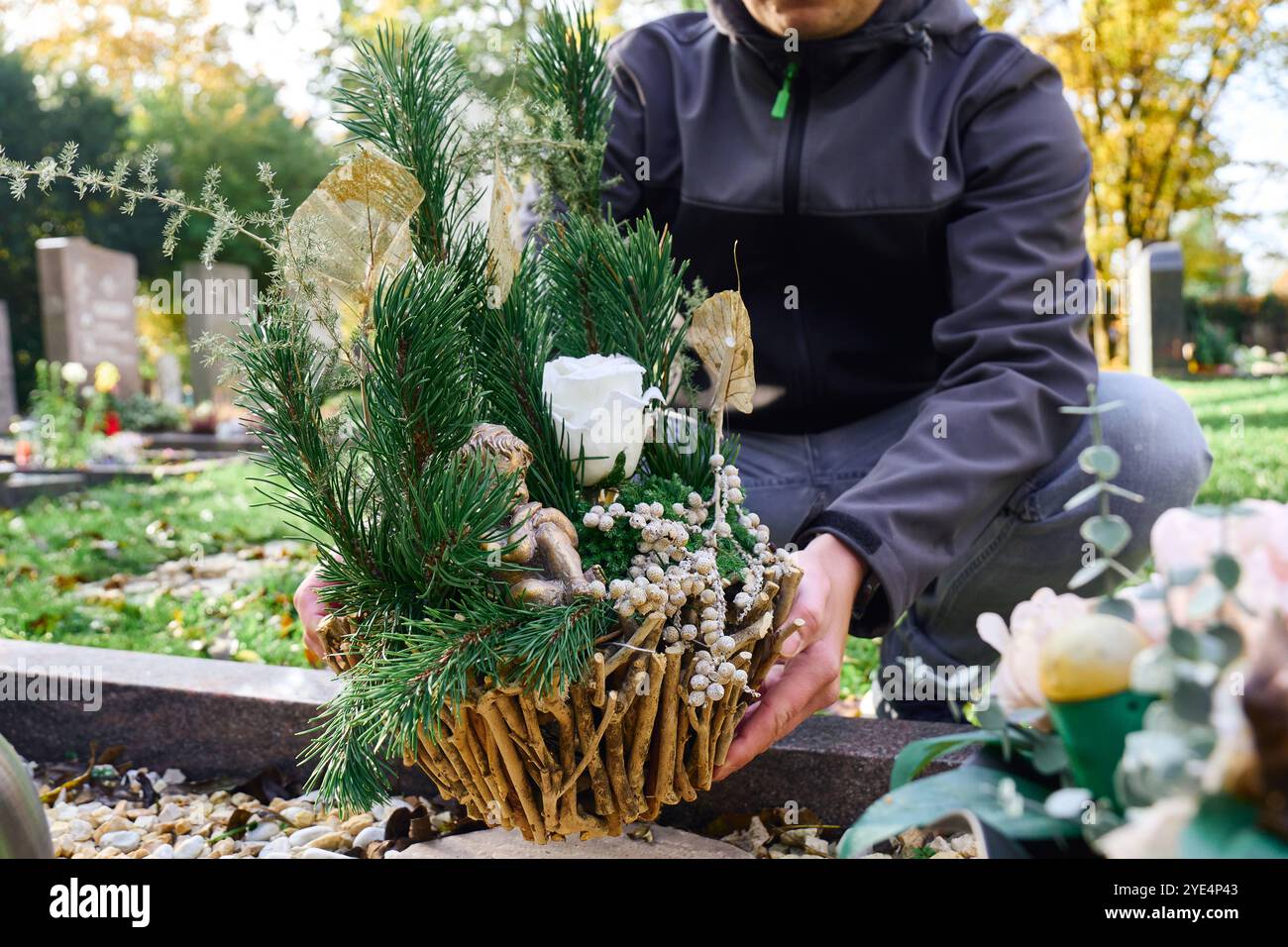 Bavaria, Germany - October 29, 2024: Man places a grave arrangement on ...