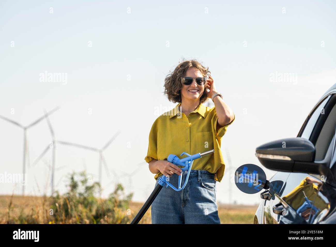 Woman holds a hydrogen fueling nozzle. Refueling car with hydrogen fuel ...