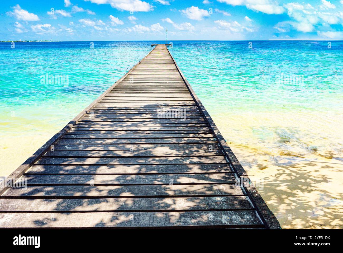 Shoreline and wooden jetty extending into the Indian Ocean. Maldives ...