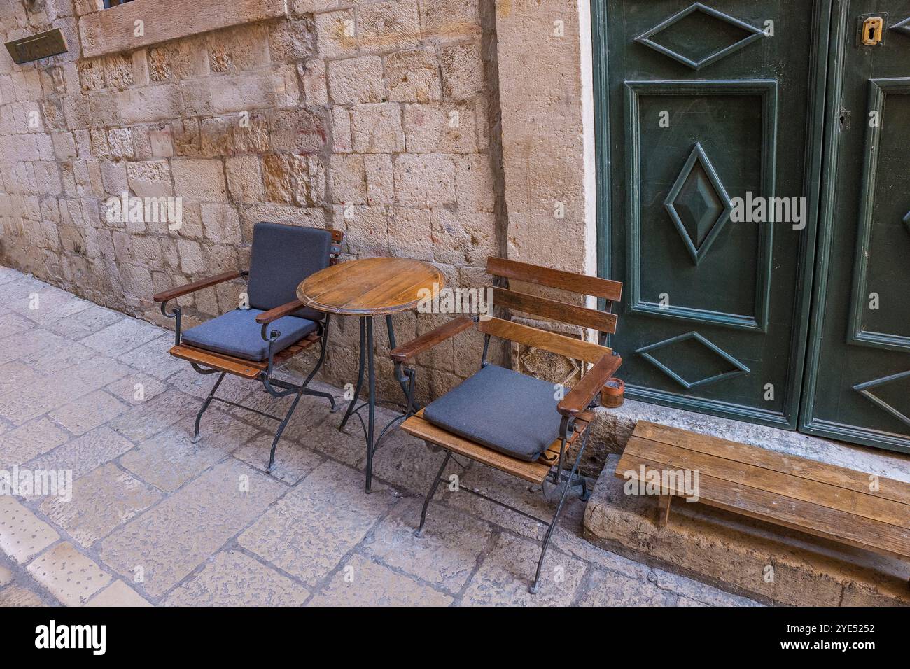 Empty chairs and table on the stone street of medieval town Stock Photo ...
