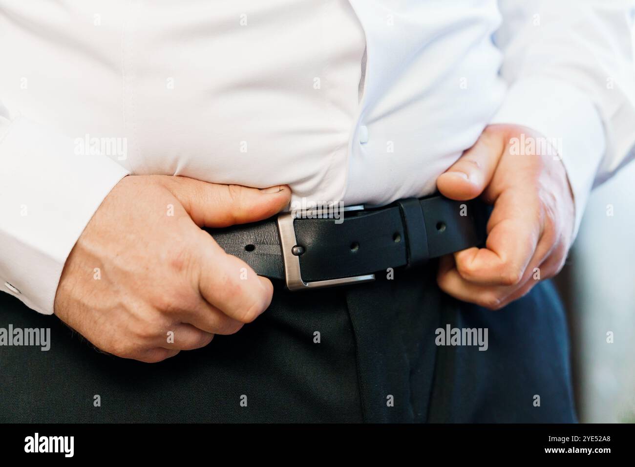 Man Adjusting His Belt While Wearing a White Dress Shirt Stock Photo ...