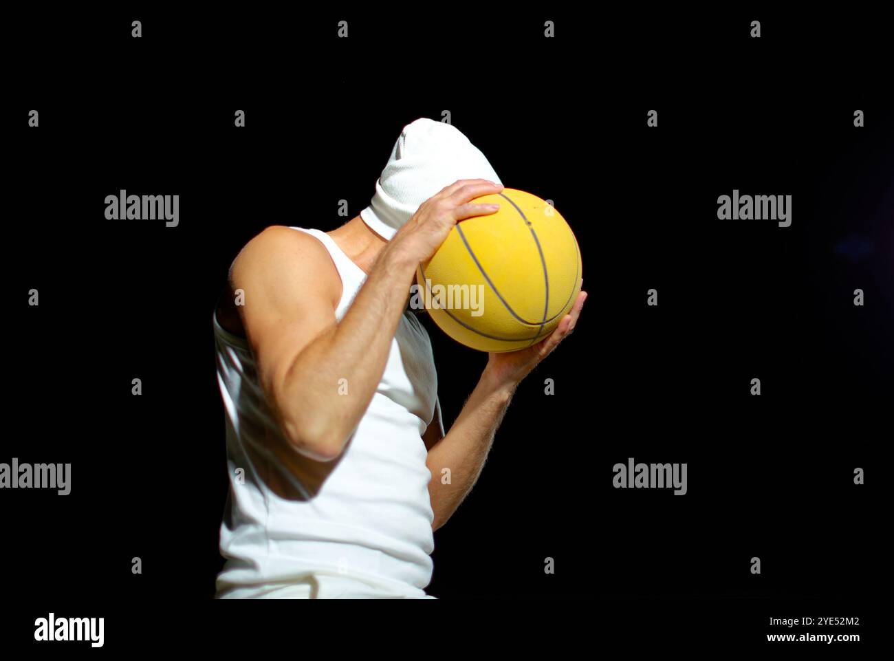 A man dressed in a white tank top and beanie strikes a dynamic pose ...