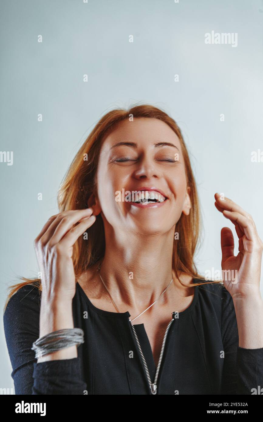 Joyful woman with closed eyes is laughing and moving her hands ...