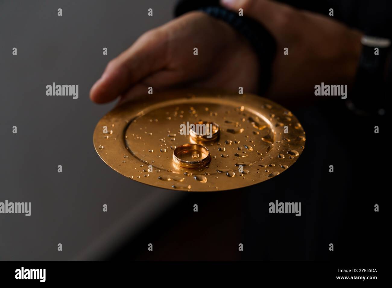 Reflective Moments: Wedding Rings on a Gold Plate with Water Droplets ...