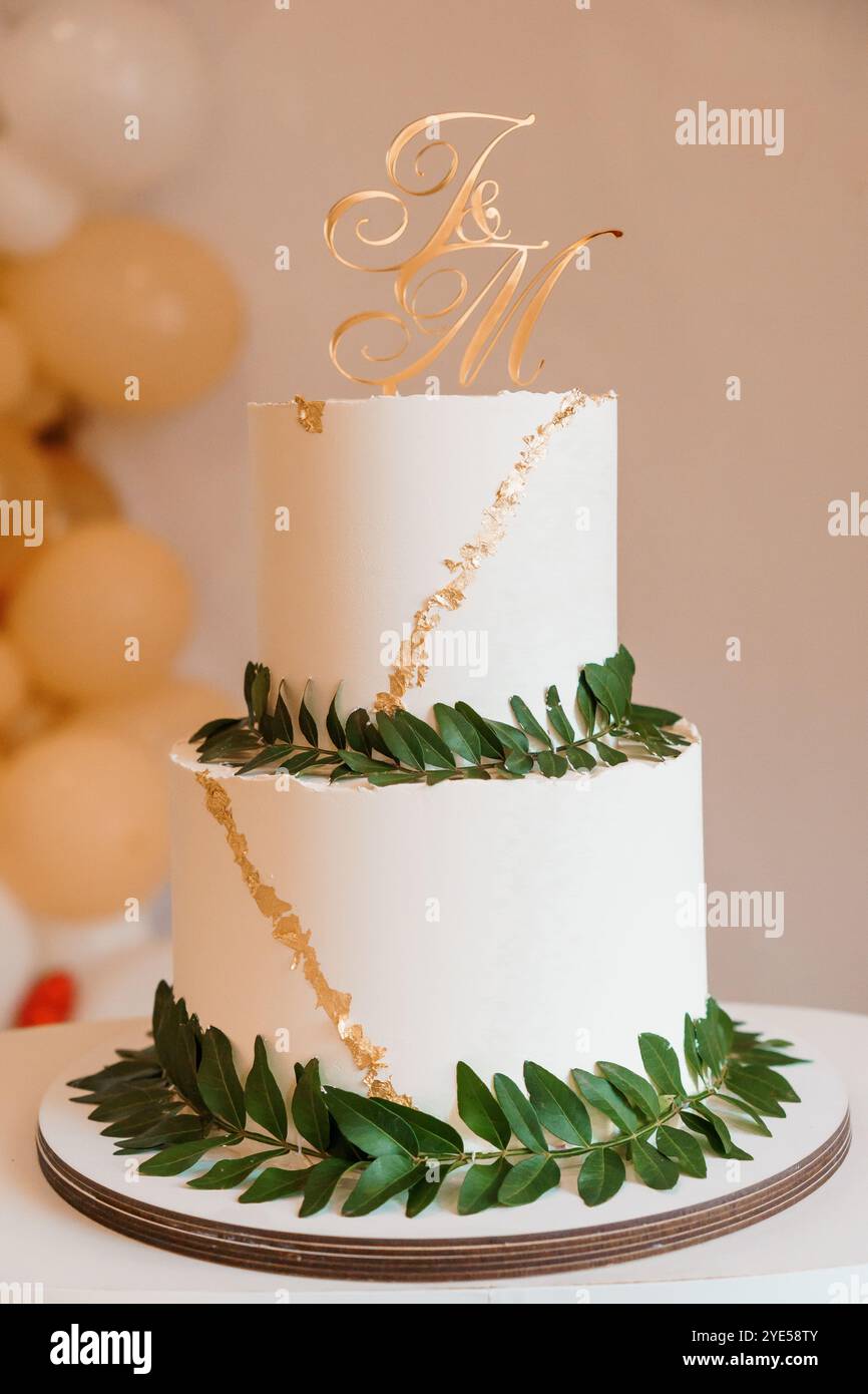 Elegant Two-Tier Wedding Cake with Gold Accents and Greenery Stock ...
