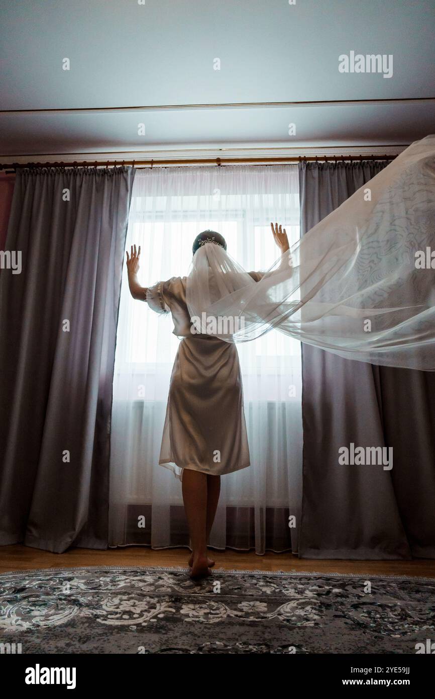 Ethereal Bride Gazing Out the Window with Flowing Veil Stock Photo - Alamy