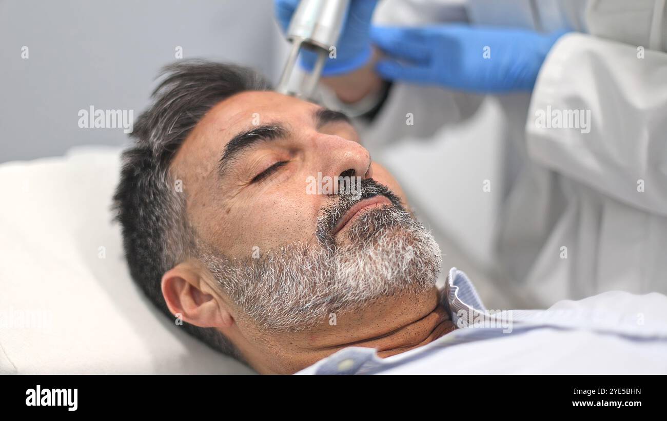 Doctor performing a skin treatment on a male patient with an advanced ...