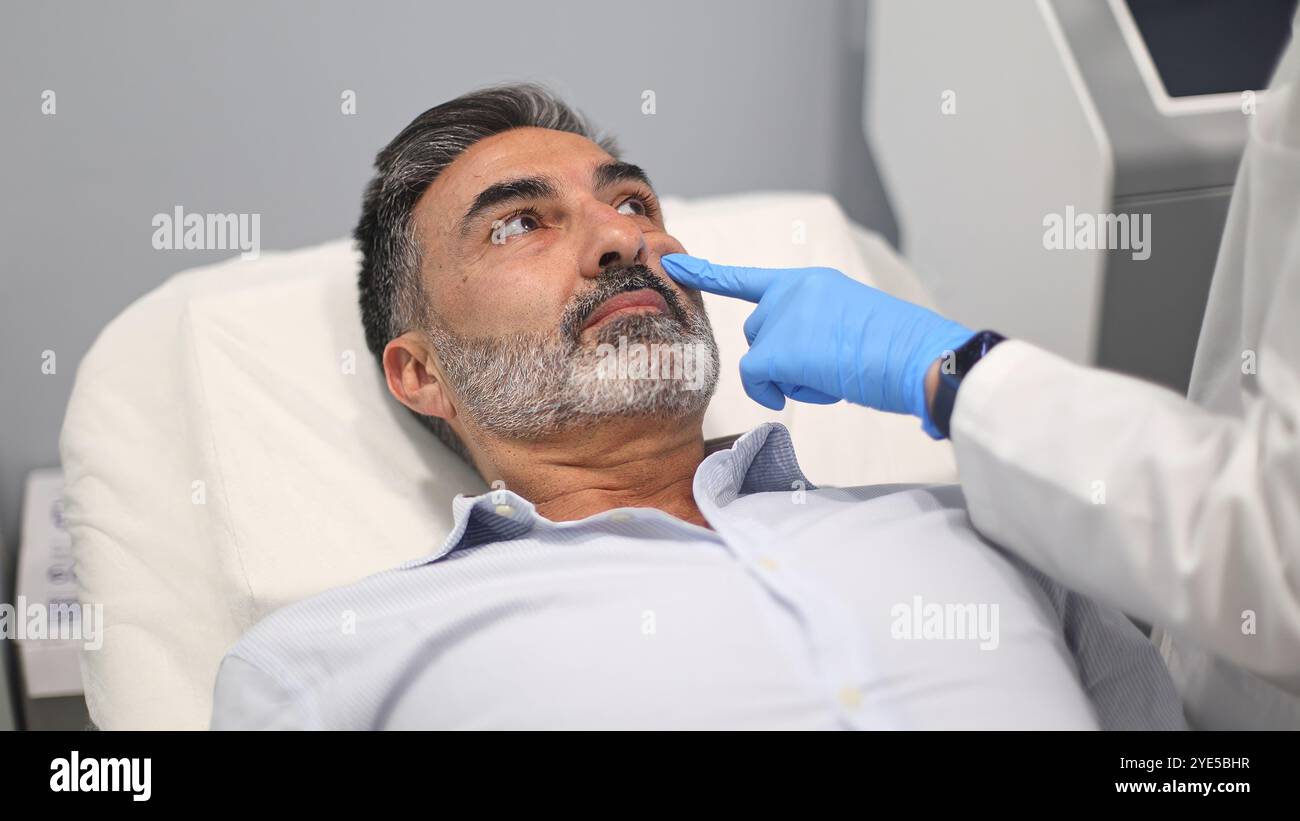 Doctor examining a male patient's face before a cosmetic procedure at a ...
