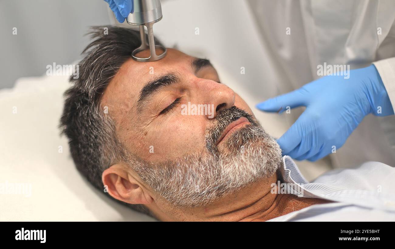 Doctor performing a non-invasive skin treatment on a male patient at a ...