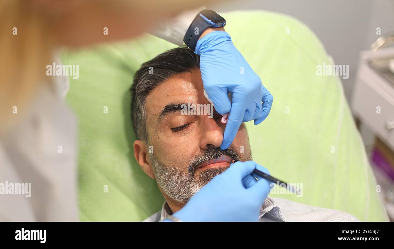 Doctor preparing a male patient's face with markings and a cloth for a ...