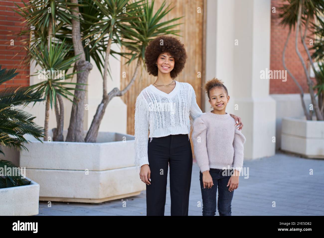 Two young sisters dressed in casual clothes are standing with cheerful ...