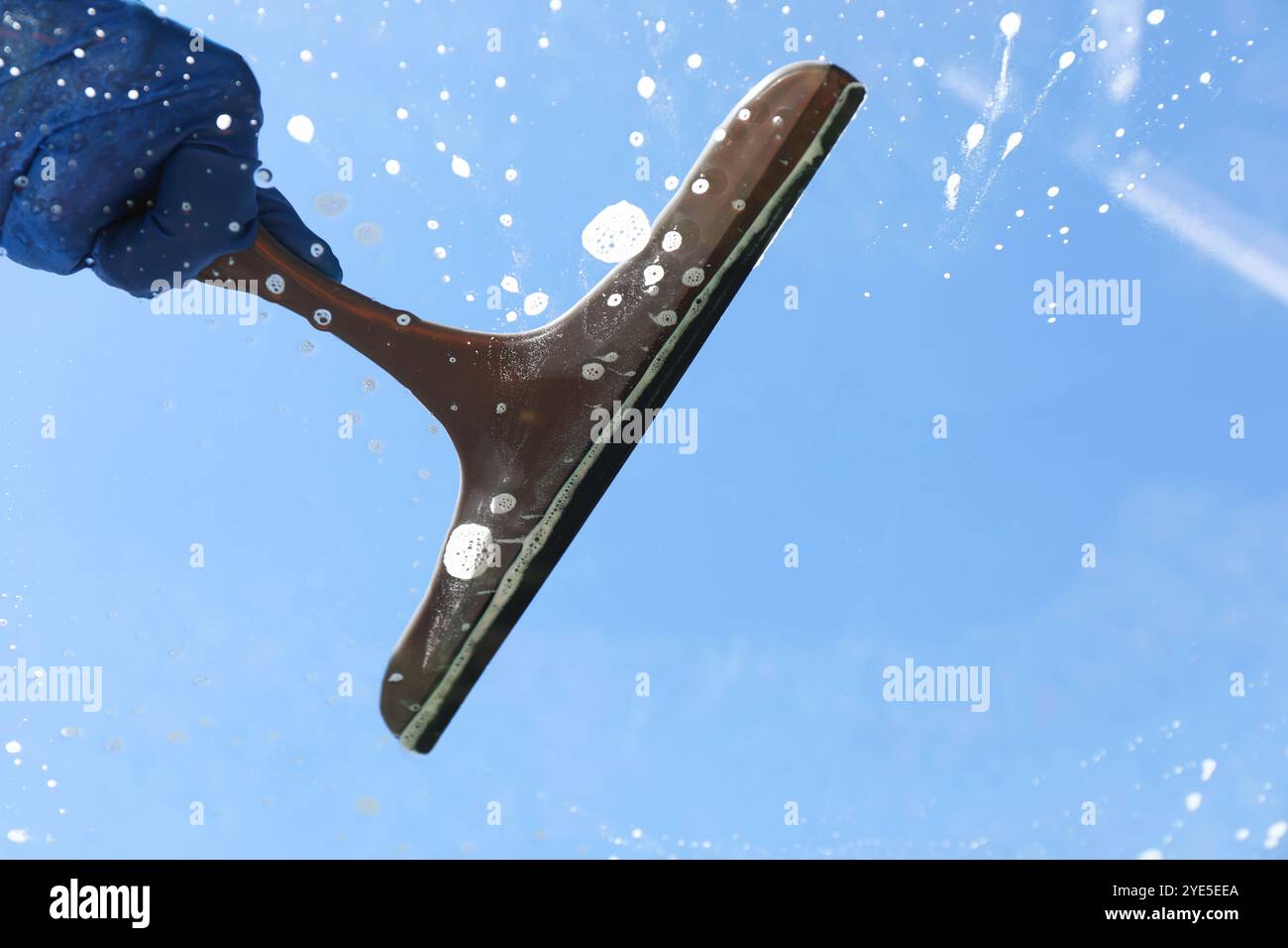 Woman washing window with squeegee tool against blue sky, closeup Stock ...
