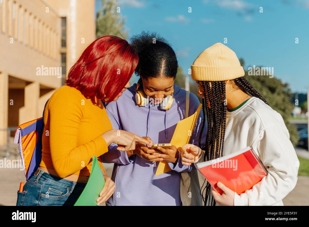Three college students, each with unique hairstyles, look at a ...