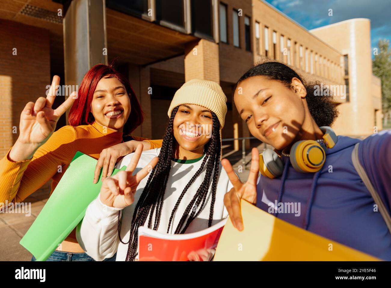 Three young college students sharing a joyful moment on campus, with ...