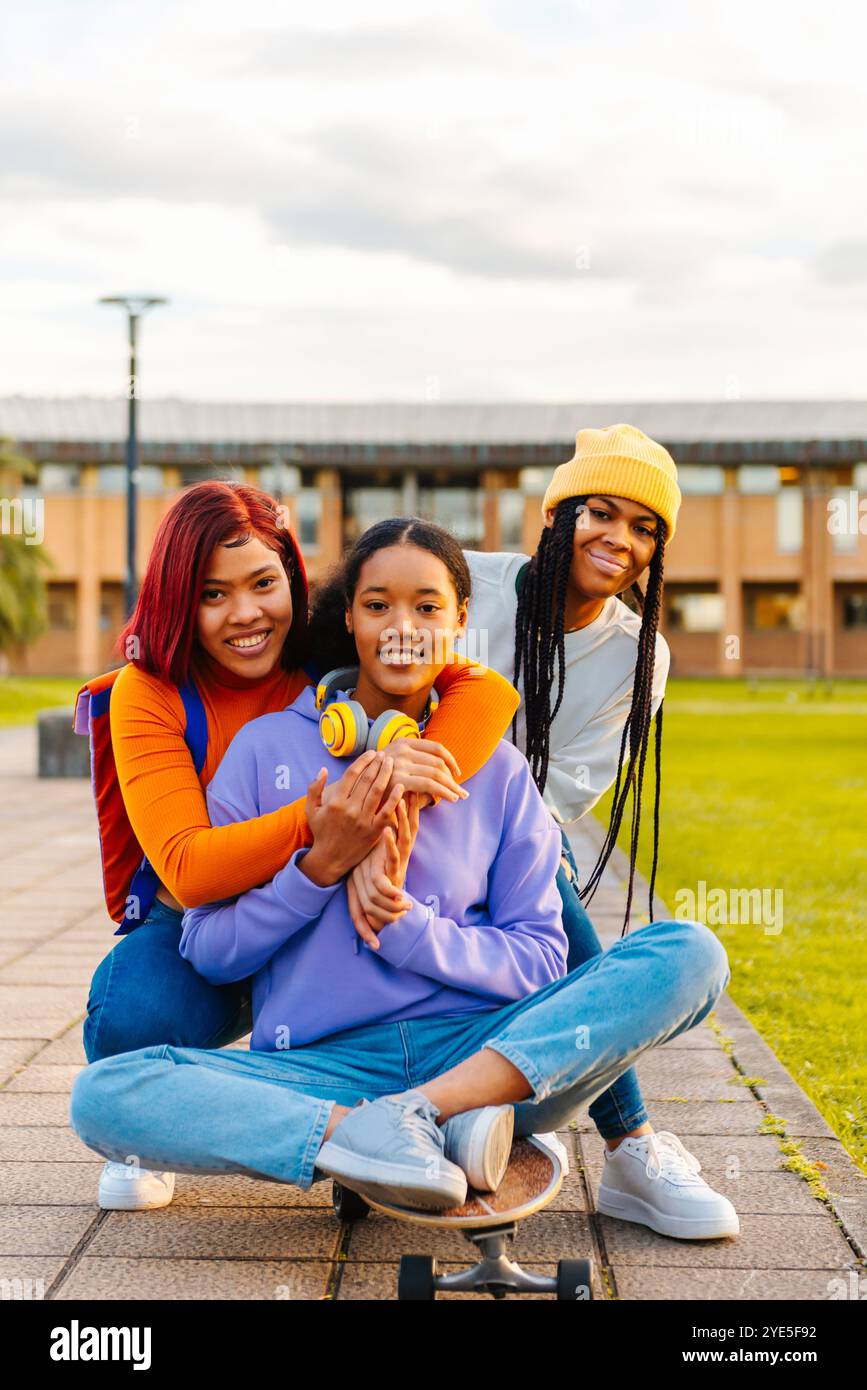 Three happy female students sharing smiles and fun moments seated on a ...