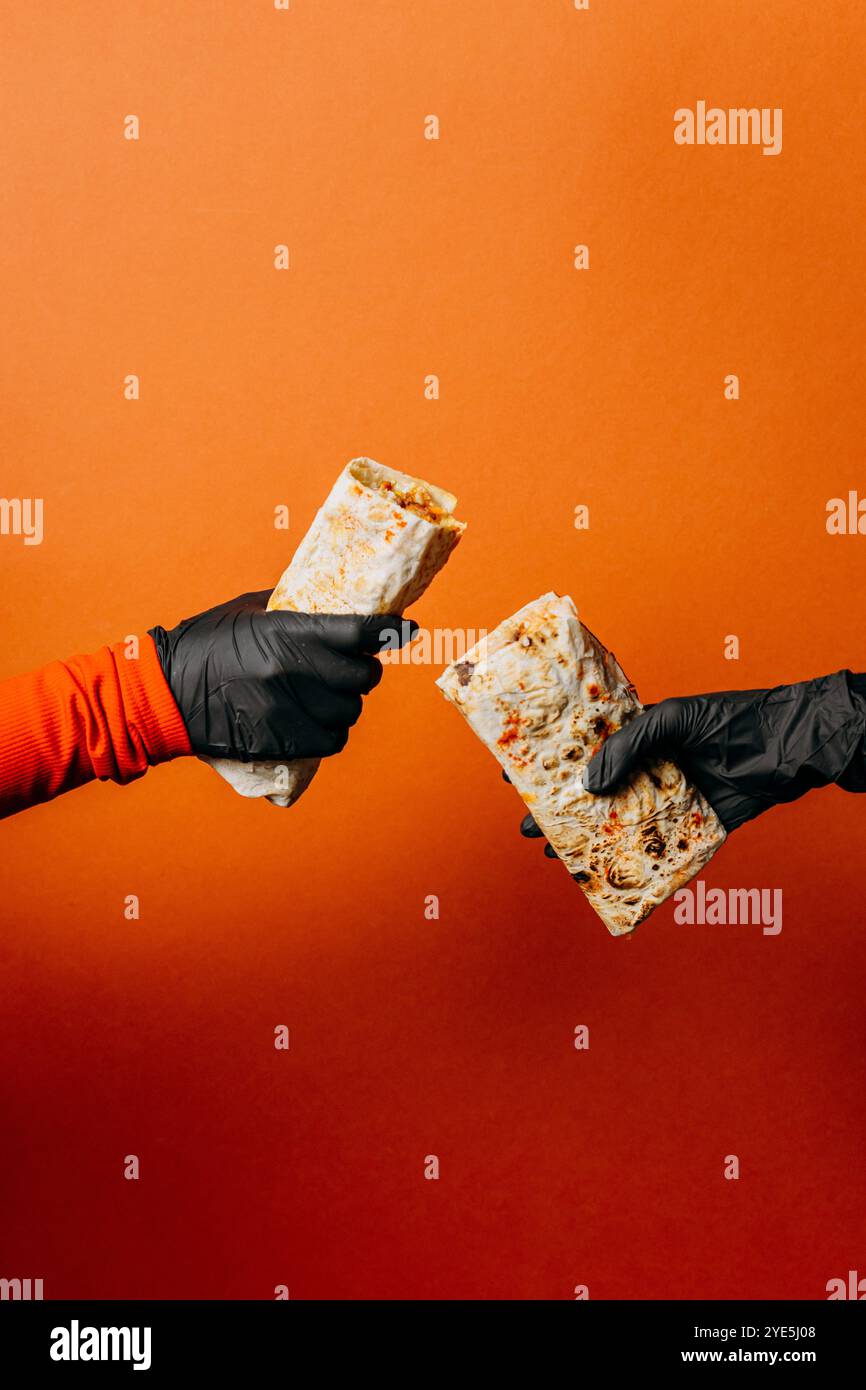 Two hands exchanging wraps in black gloves on an orange background ...