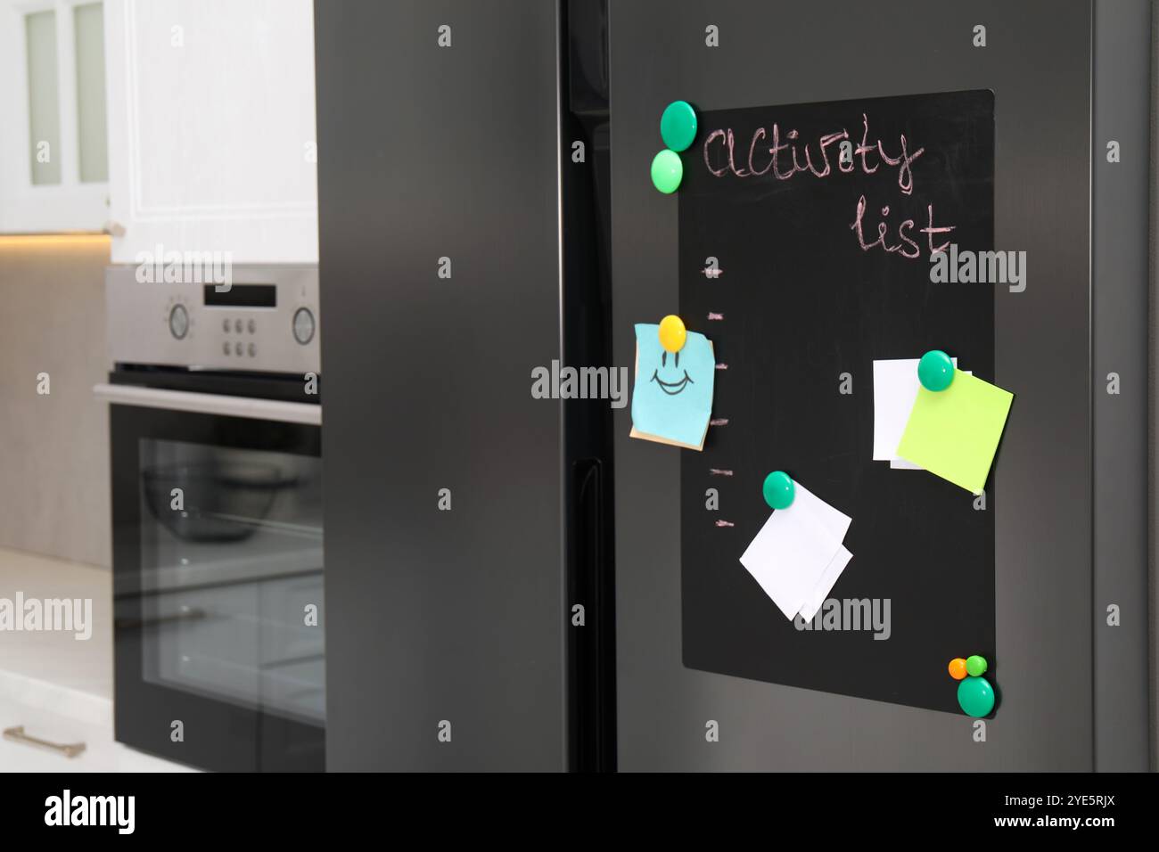 Magnetic board with activity list and notes on refrigerator in kitchen ...