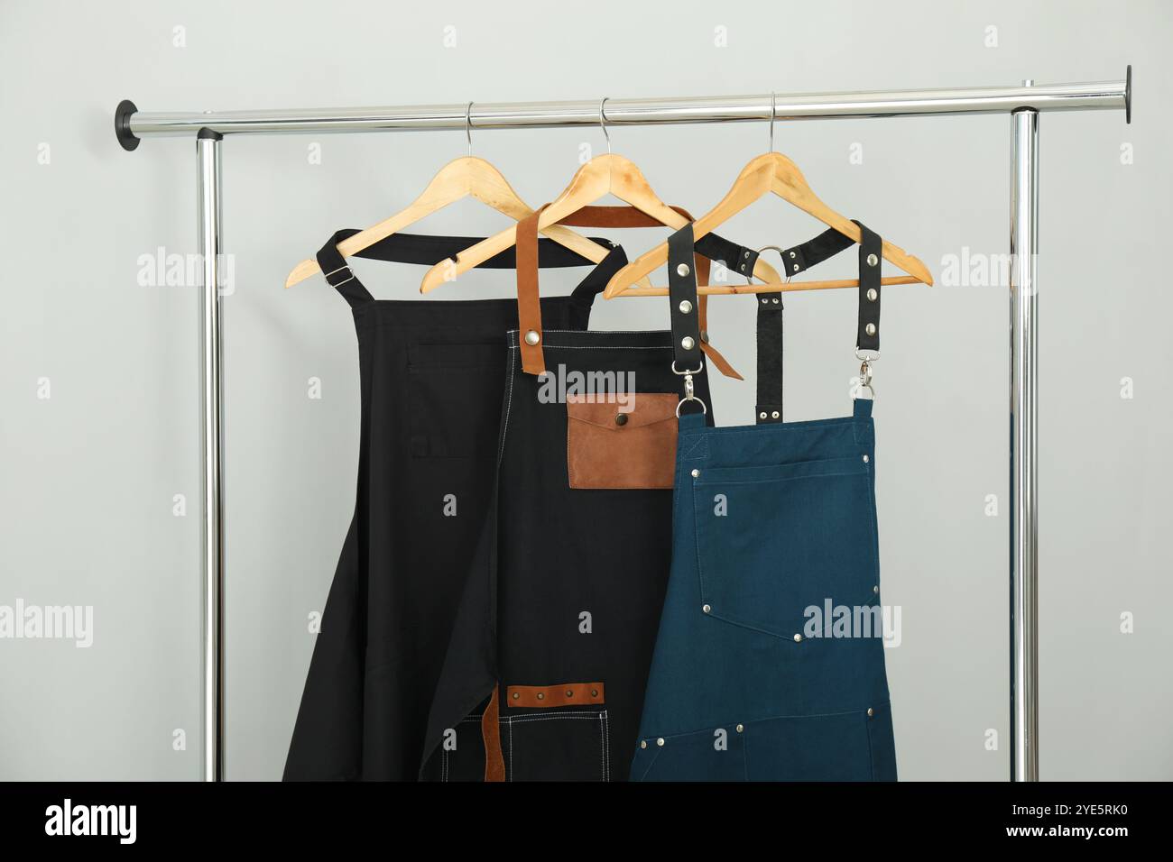 Aprons on clothing rack near light grey wall Stock Photo - Alamy