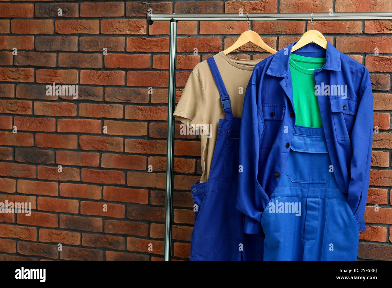 Workers' uniforms on clothing rack near brick wall, space for text ...