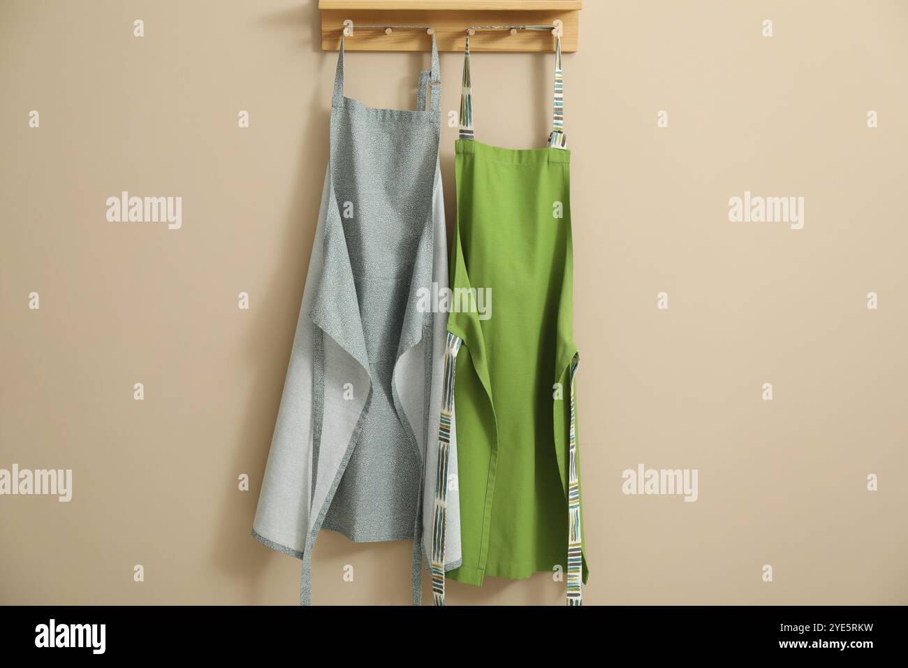 Two chef's aprons hanging on beige wall Stock Photo - Alamy