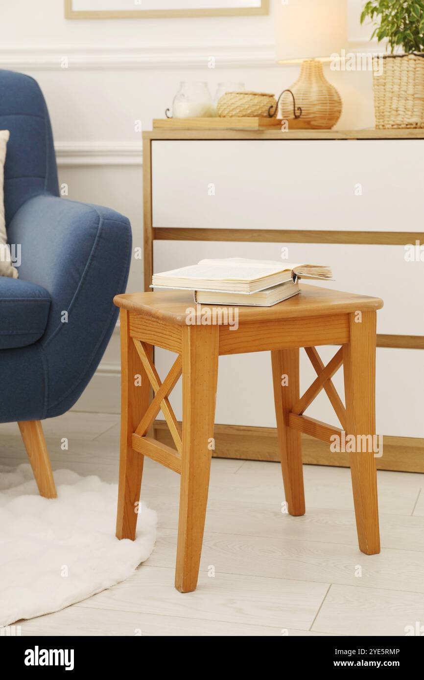 Stool, books, armchair and houseplant in room. Interior design Stock ...