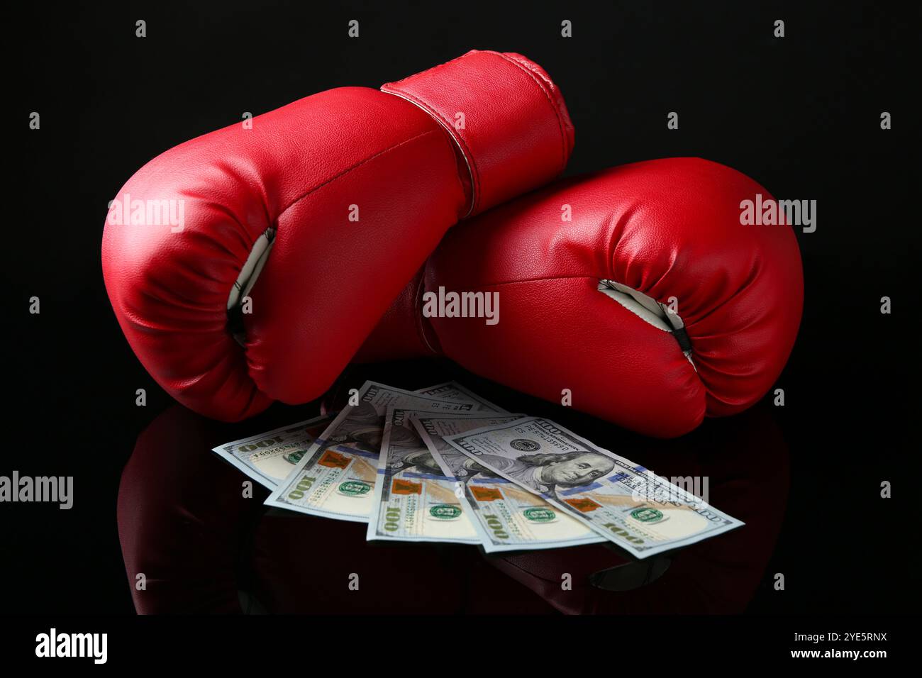 Pair of red boxing gloves and dollar banknotes on black mirror surface ...