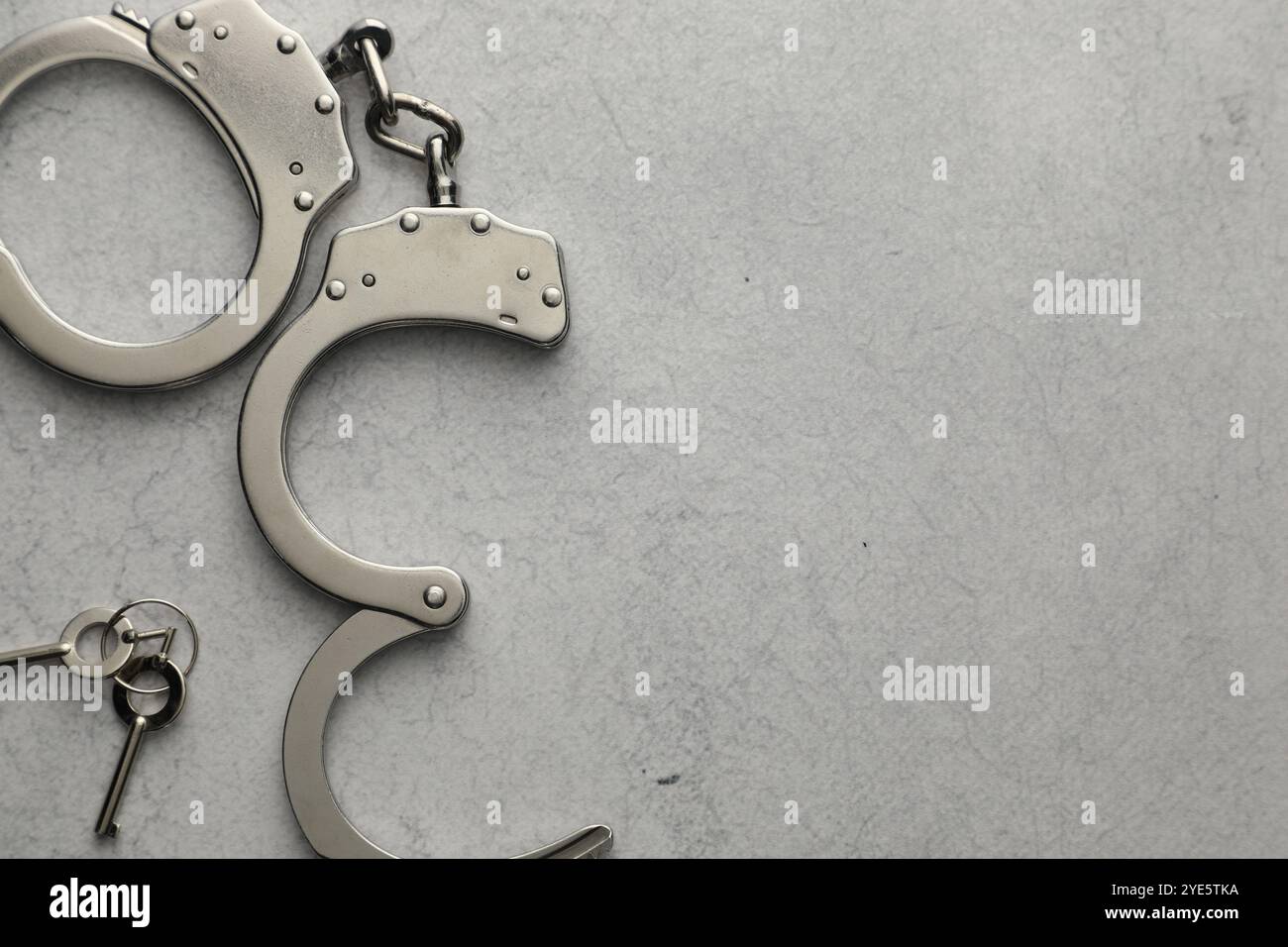 Metal chain handcuffs and keys on light grey table, top view. Space for ...