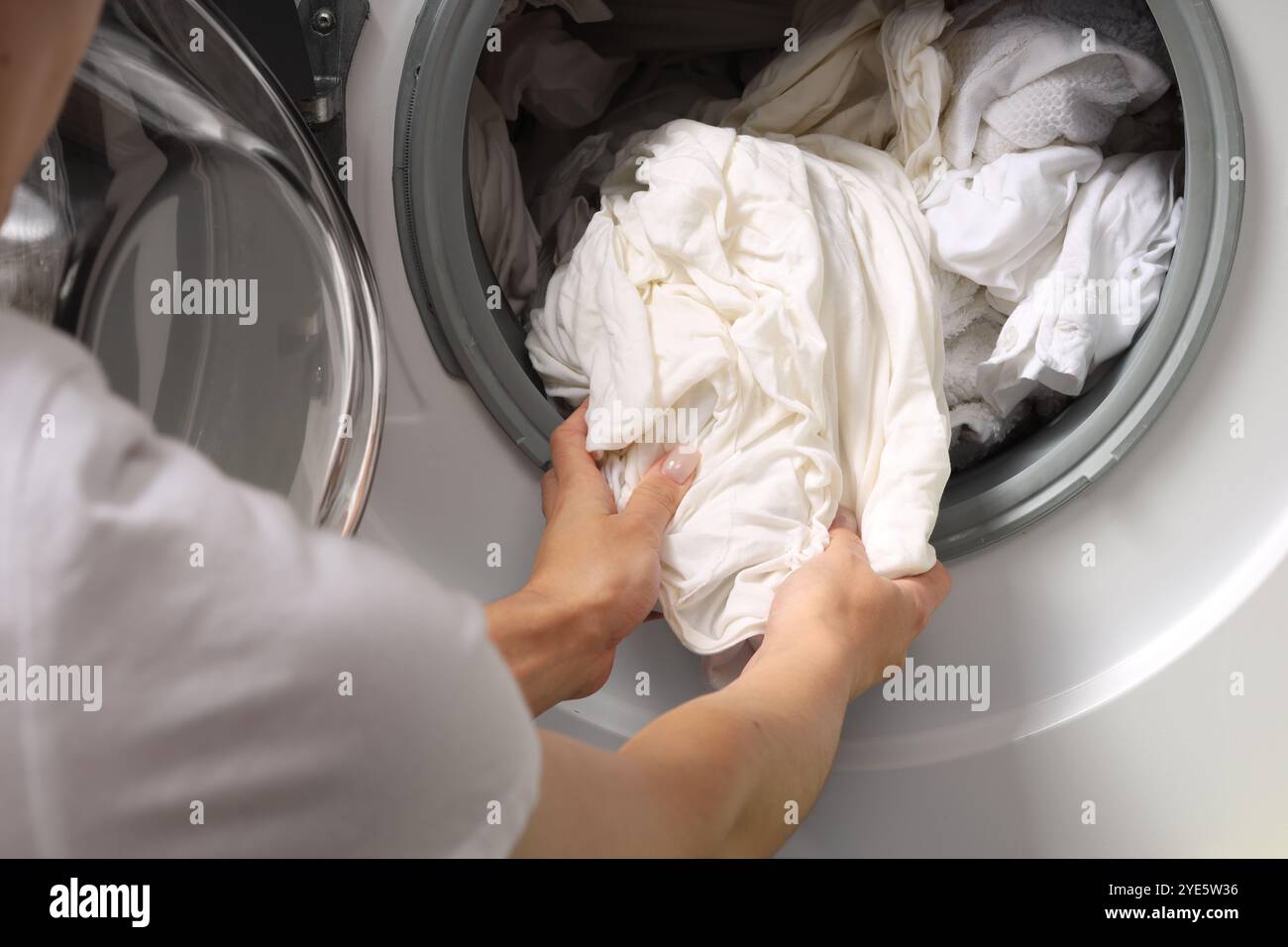 Woman taking clean clothes out of washing machine, closeup Stock Photo ...