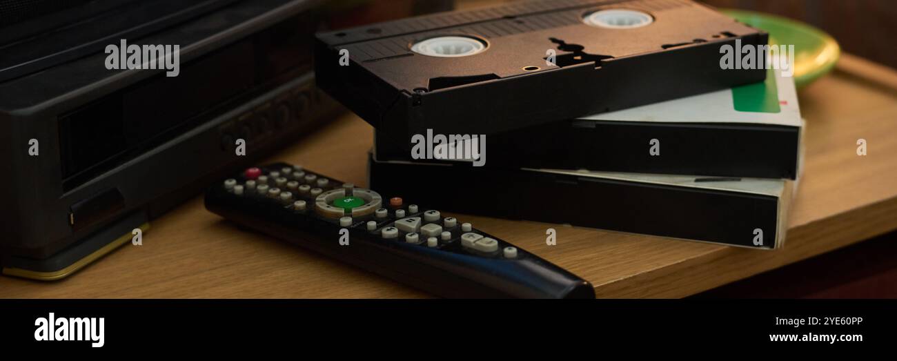 Close-up of several retro VHS tapes stacked near television remote ...