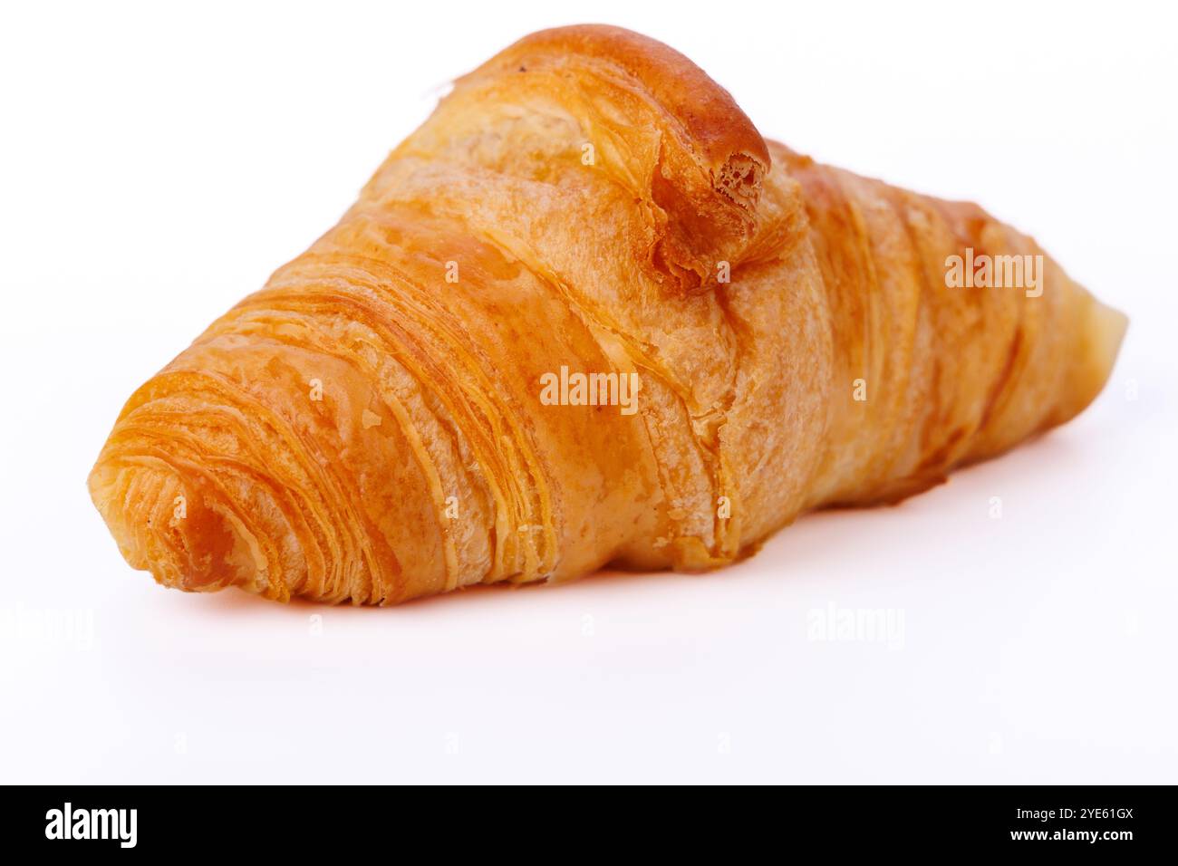 A croissant is featured on a pure white background, bringing attention to its crisp texture and ...