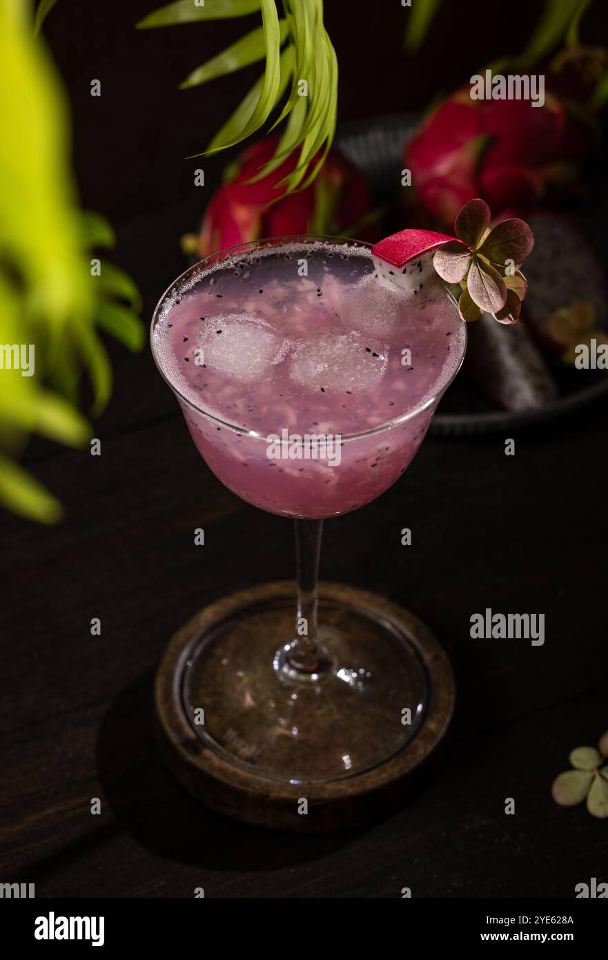 Vibrant pink dragon fruit cocktail is being served in elegant glass ...