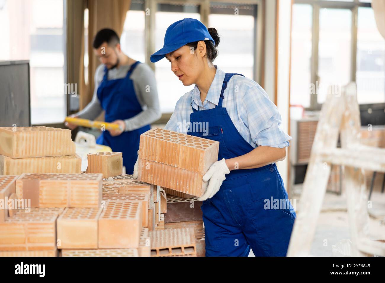 Female builder preparing red bricks in building under reconstruction ...