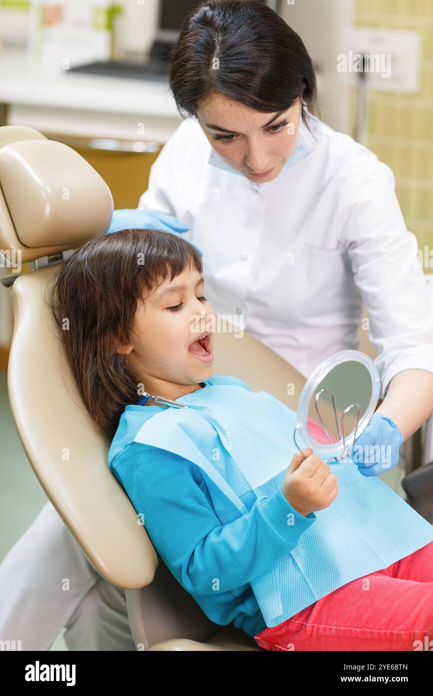 Dentist showing to little patient her teeth in mirror Stock Photo - Alamy